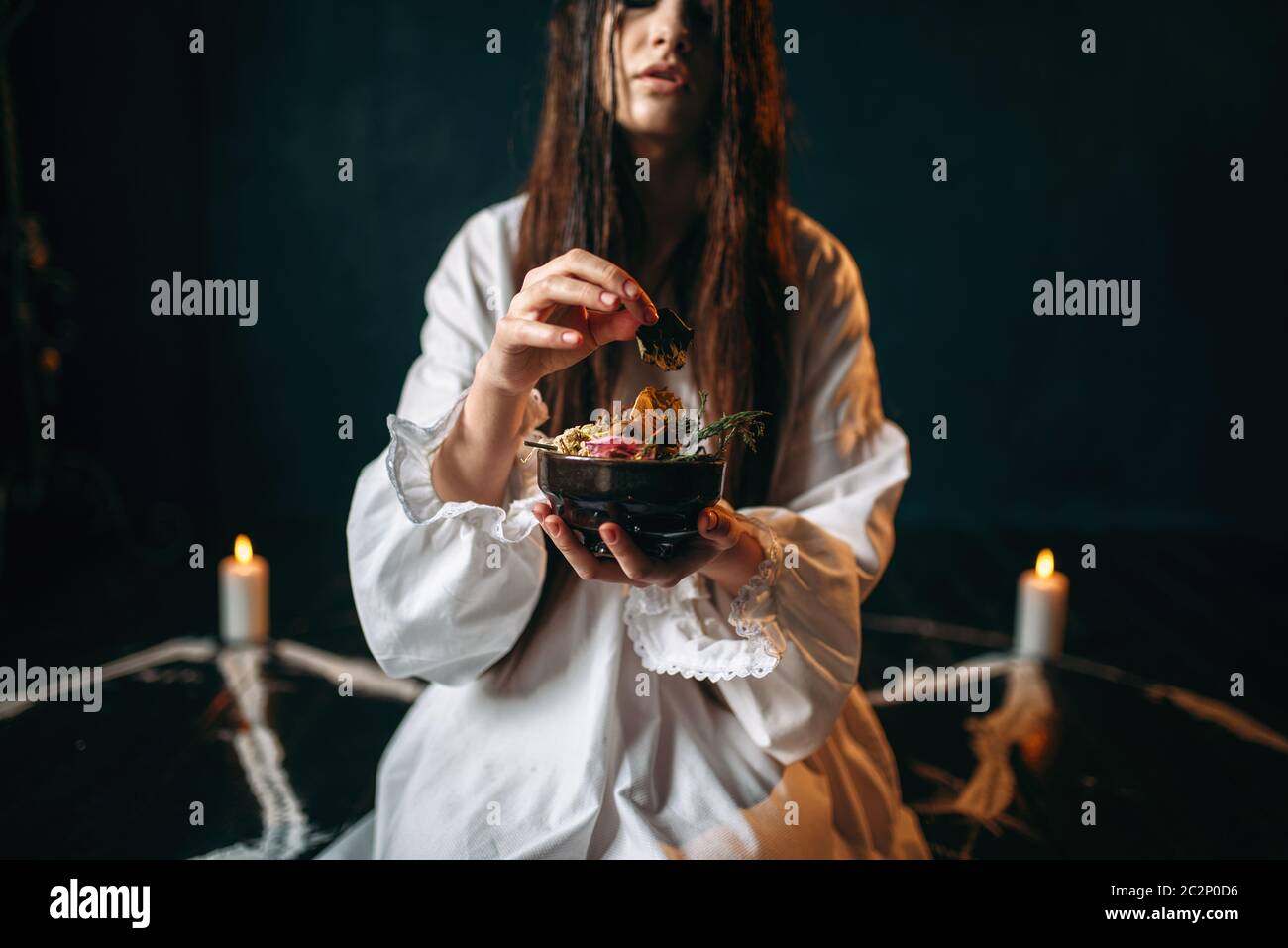 Young woman in white shirt sitting in the center of pentagram circle ...