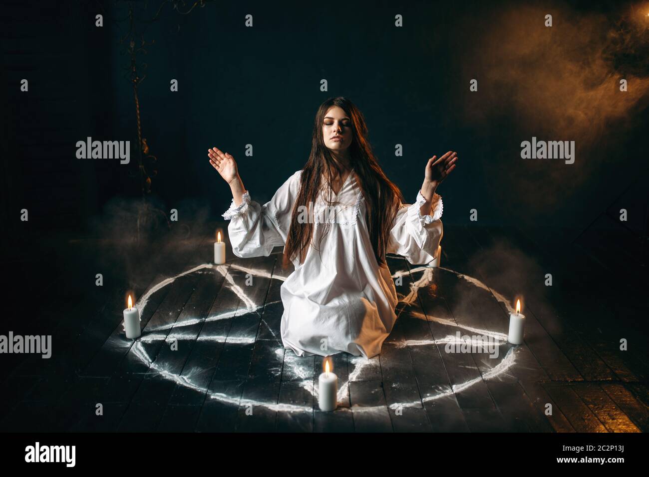 Witch in white shirt sitting in the center of pentagram circle with ...