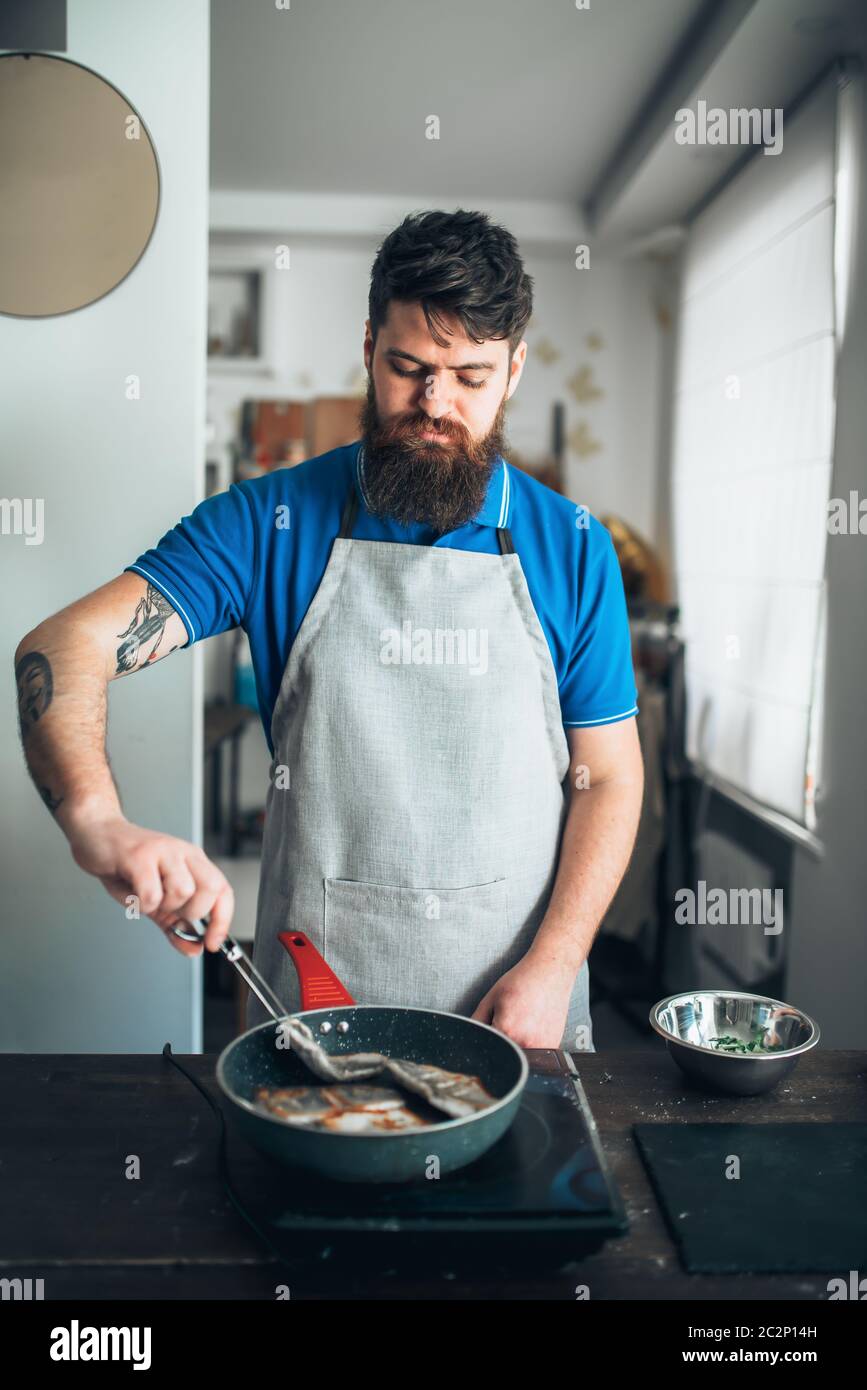 Male chef cooking sea bass fish fillet on a frying pan. Seafood ...