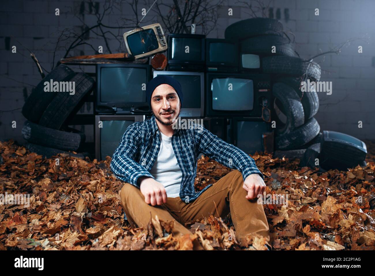 Stalker, male traveler sitting on the ground, the mountain of old TVs ...