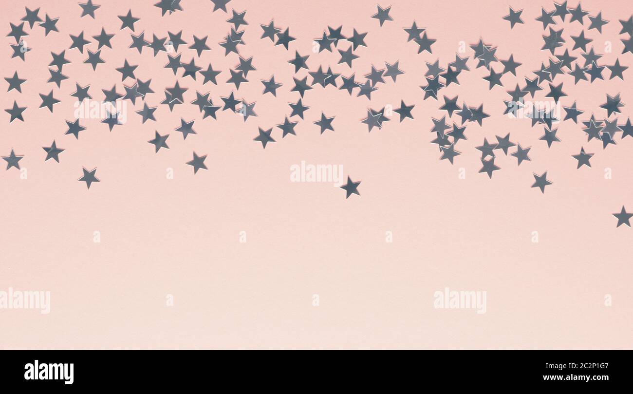 Silver plastic stars on a bright pink paper background with space for ...