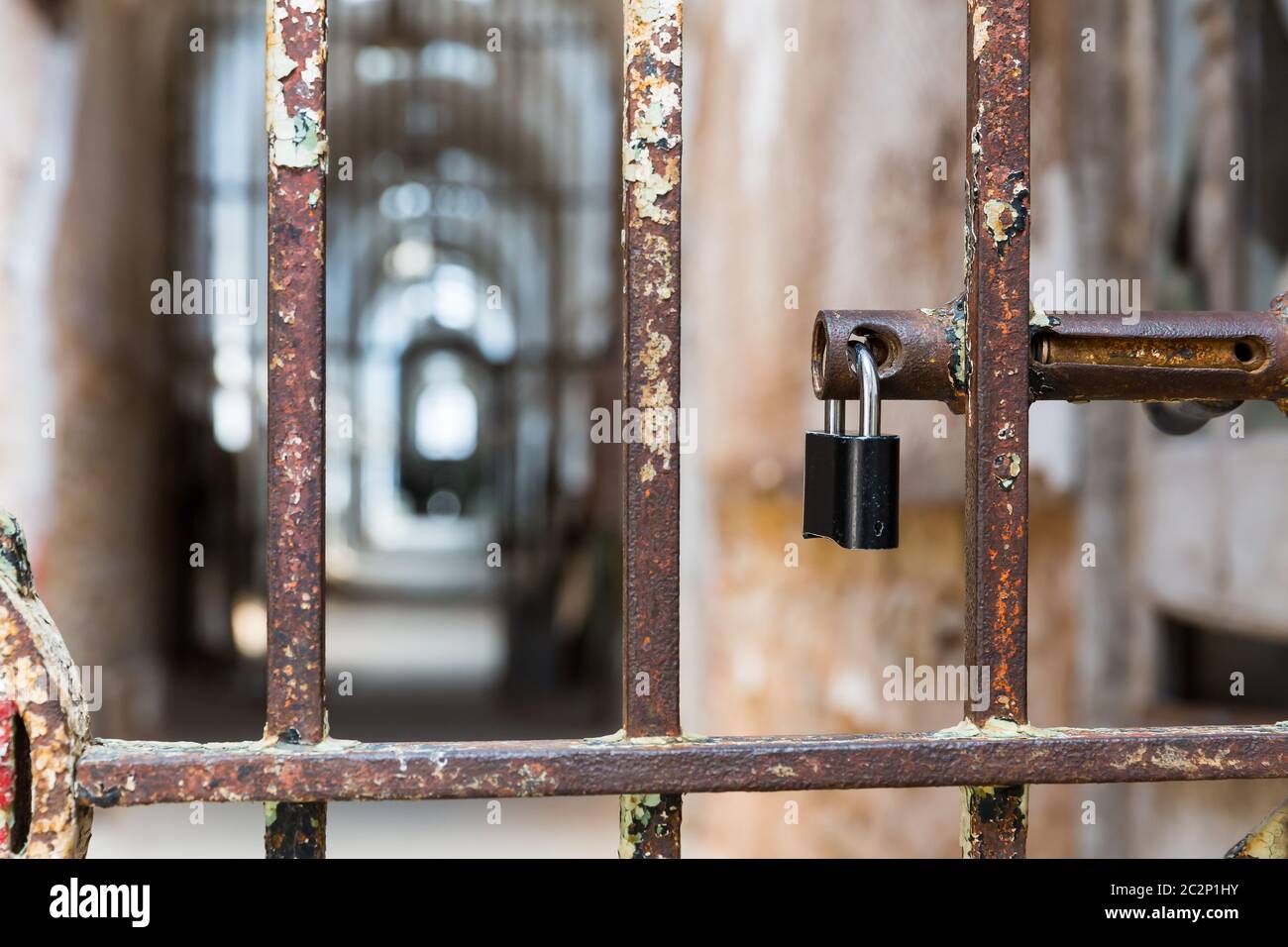 Door lock on rusty metal cell door in old prison. Blur jail hallway on ...