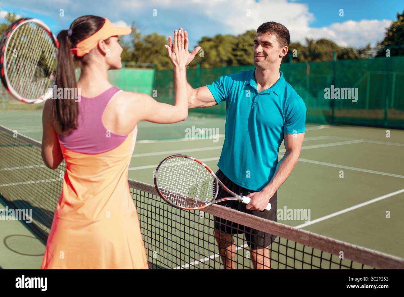 Happy couple with rackets playing on outdoor tennis court. Summer ...