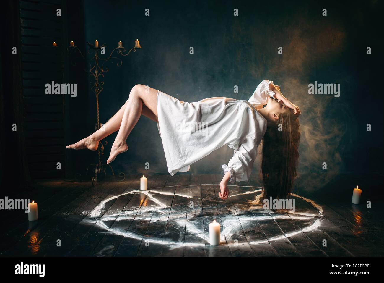 Young woman in white shirt flying over pentagram circle, gark magic ...