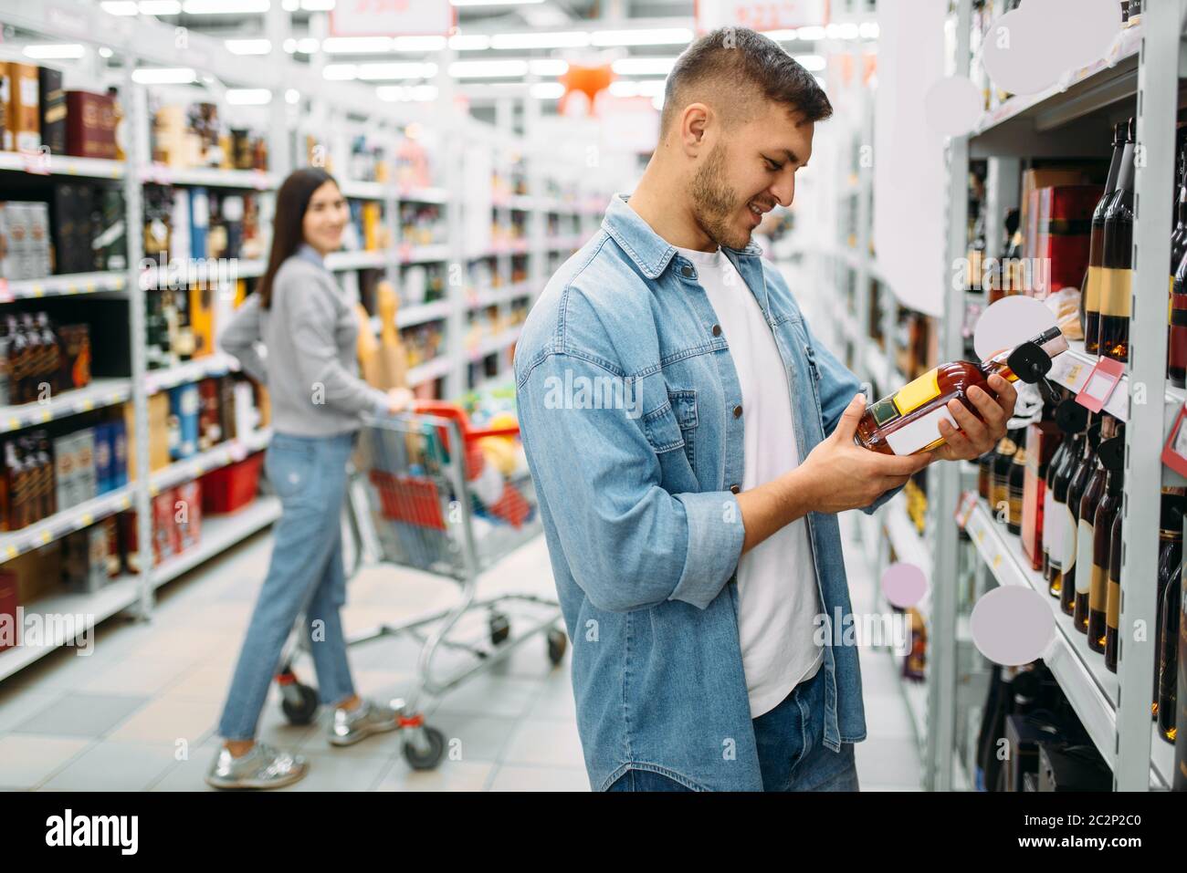 Couple with cart in supermarket, alcohol drinks department, family ...