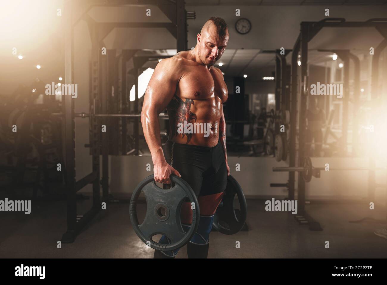 Strong male bodybuilder with pancakes from barbell. Exercise with ...