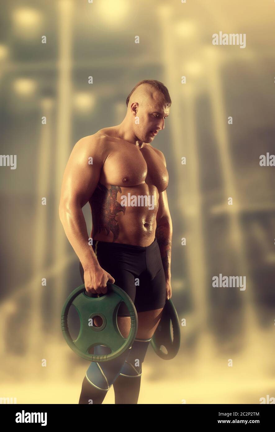 Strong male bodybuilder with pancakes from barbell. Exercise with ...