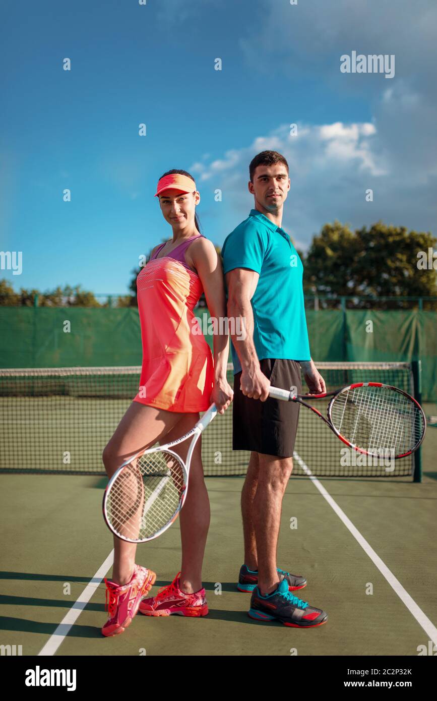 Attractive couple with tennis rackets together on outdoor court. Summer ...
