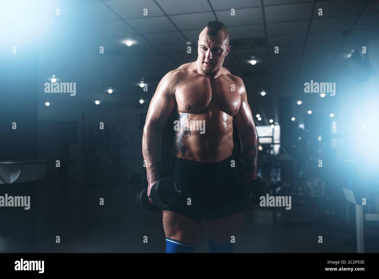 Strong male bodybuilder with pancakes from barbell. Exercise with ...