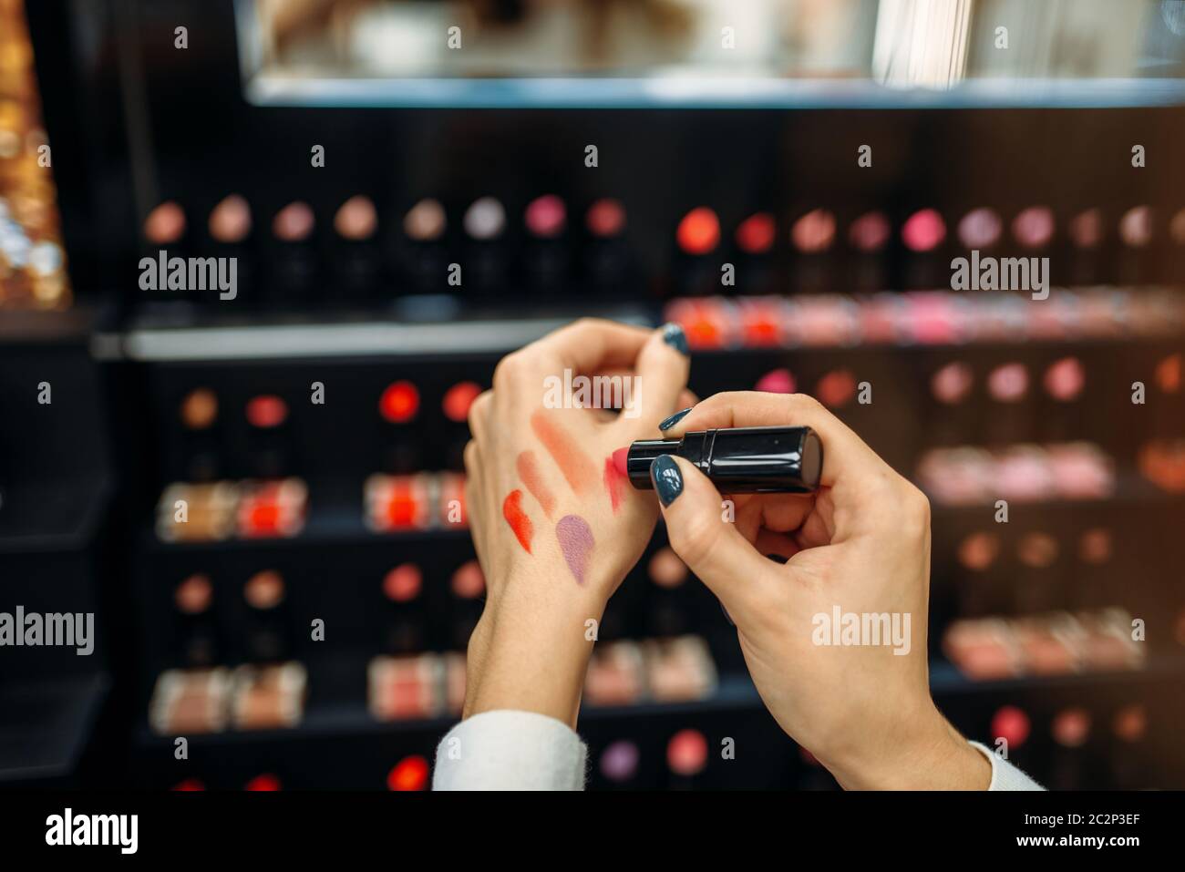 Female customer testing lipstick in the make-up shop. Cosmetics ...