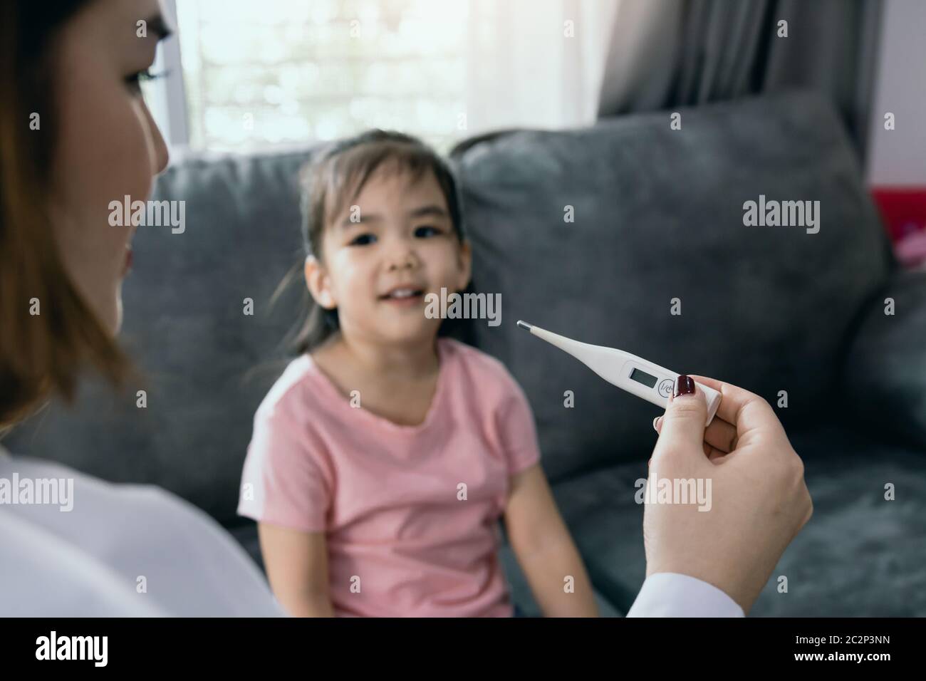 Doctor using temperature child patient in home Stock Photo - Alamy