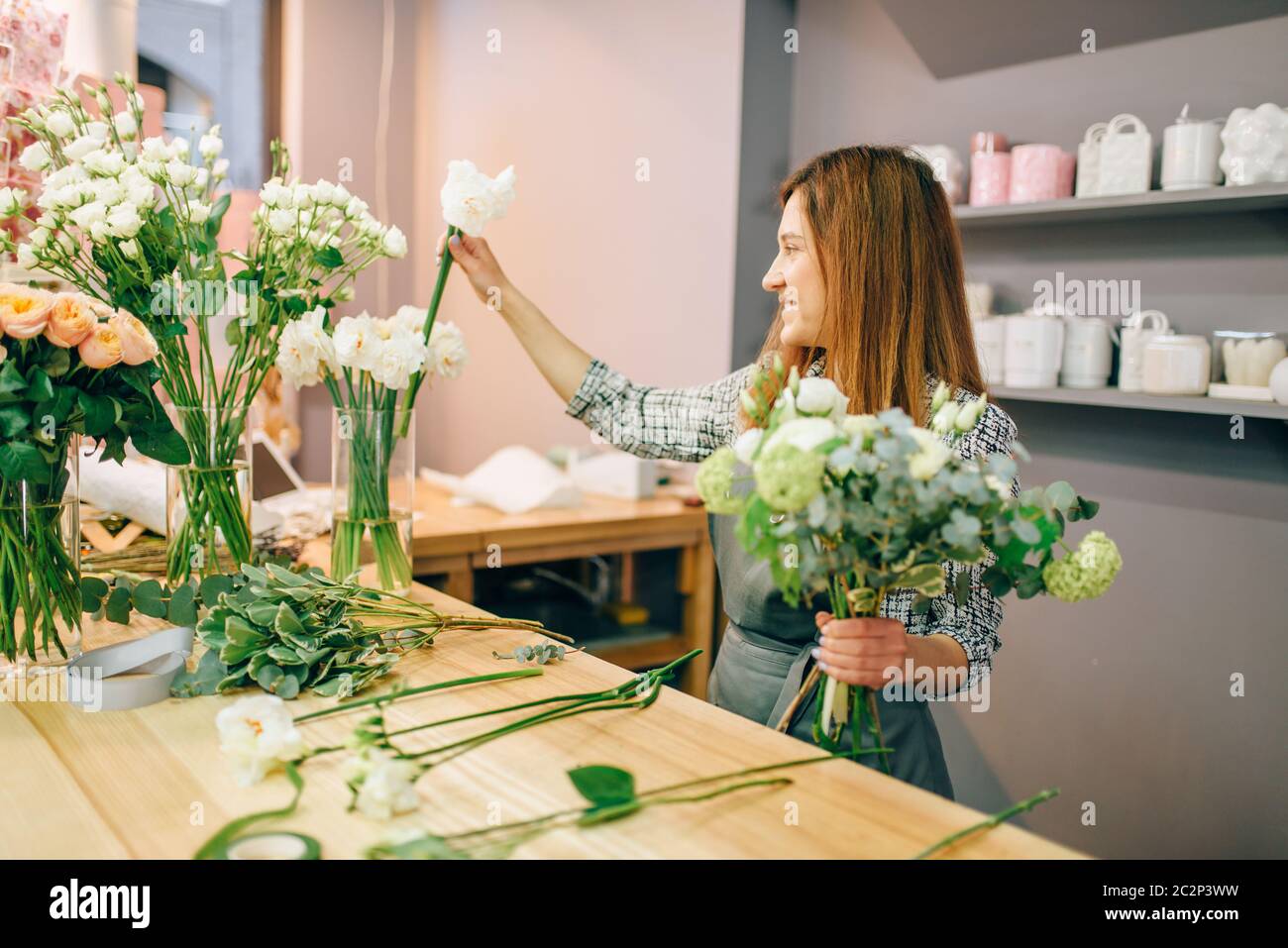 Female florist places flowers in vases, fresh bouquet preparation ...