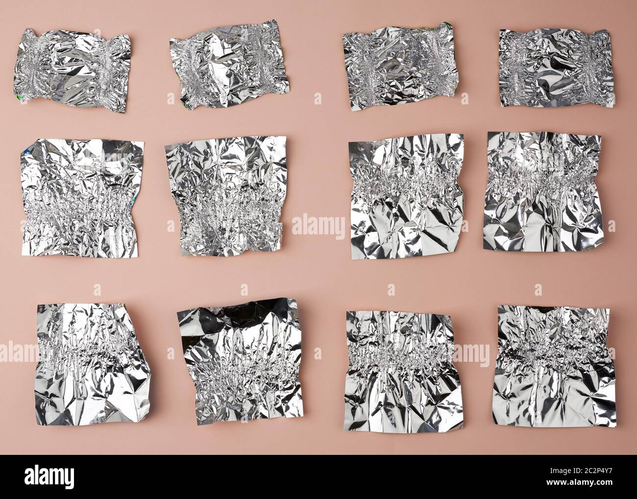 various crumpled foil used candy wrappers on a beige background, top ...