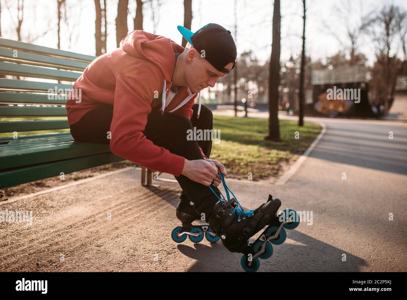 Roller skater sitting on the bench and lace up skates. Male ...