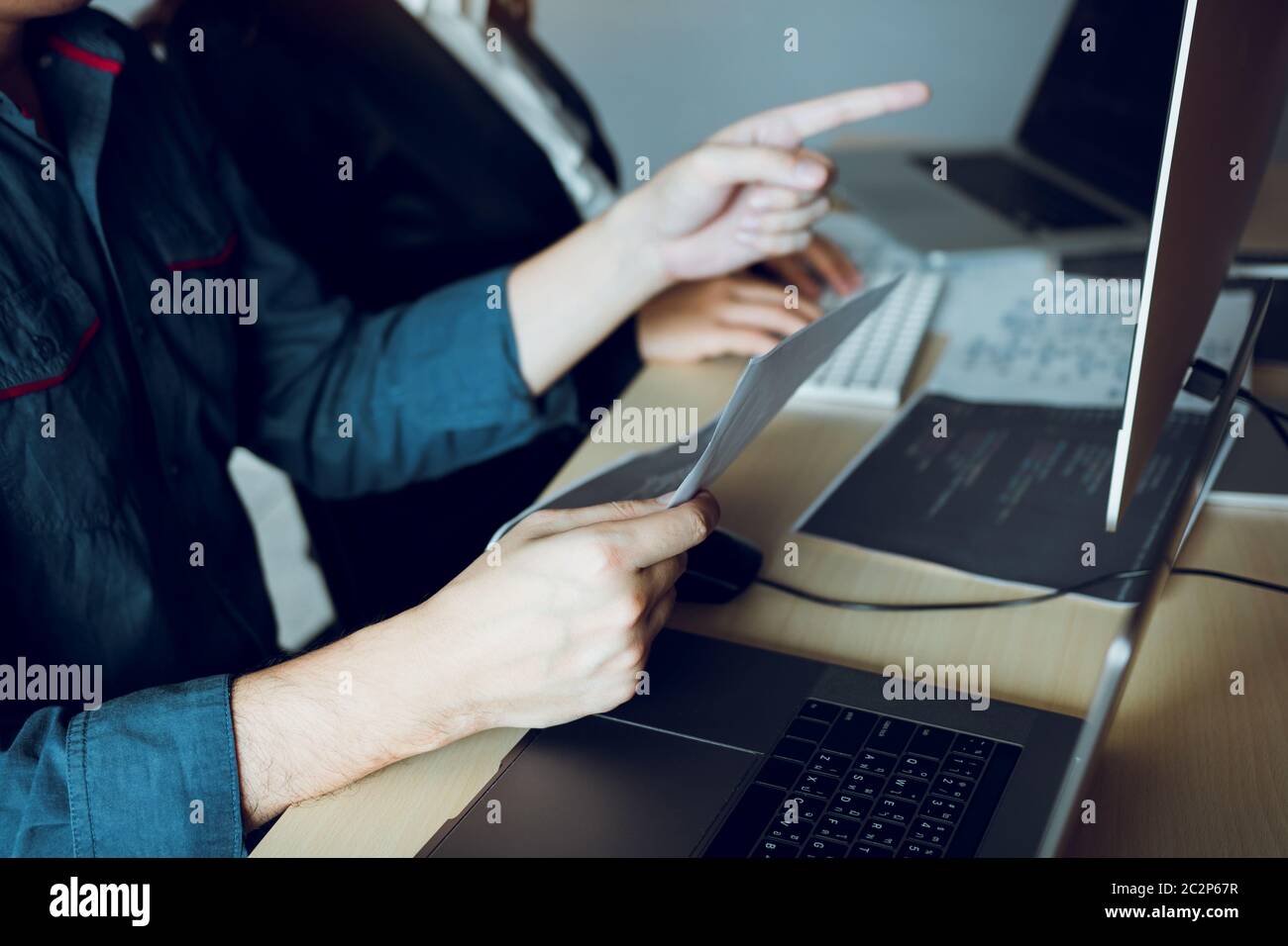 Two software developers are using computers to work together with their ...