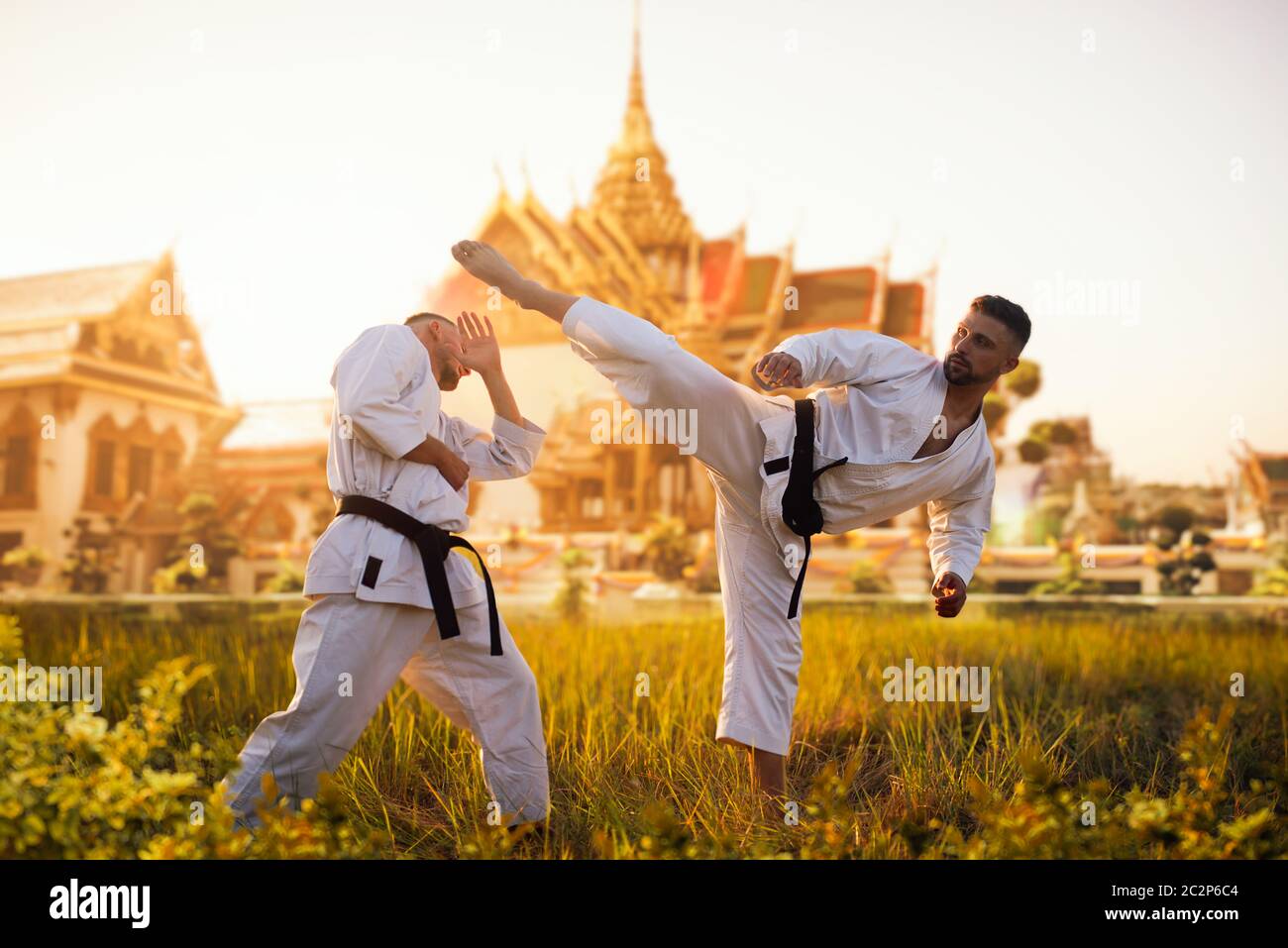 Karate fighters on training fight against ancient temple on sunset ...