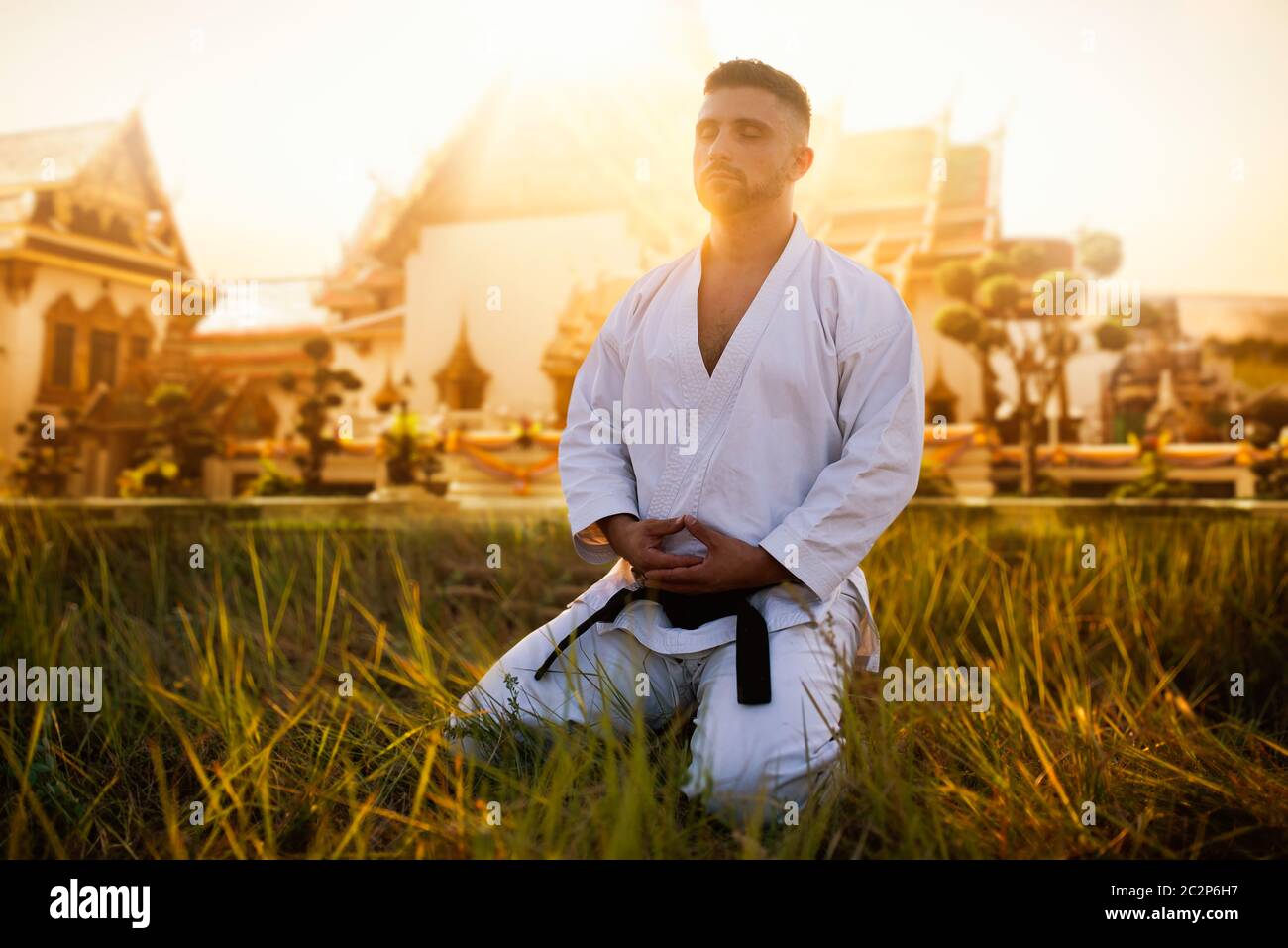 Male karate fighter sitting on the ground against ancient temple ...