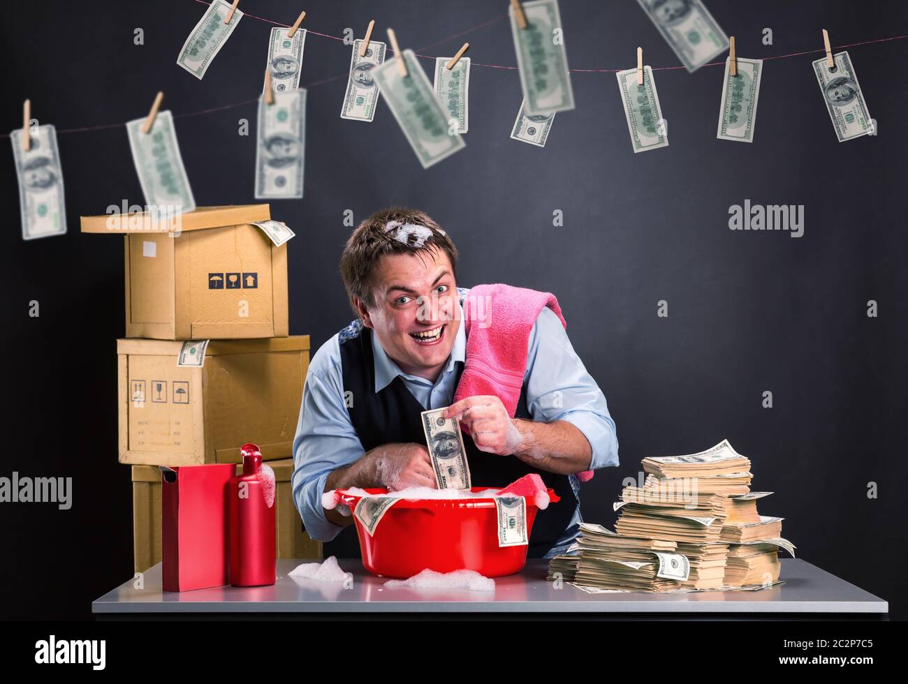 Happy businessman is laundering money banknotes in foam in red washbowl ...