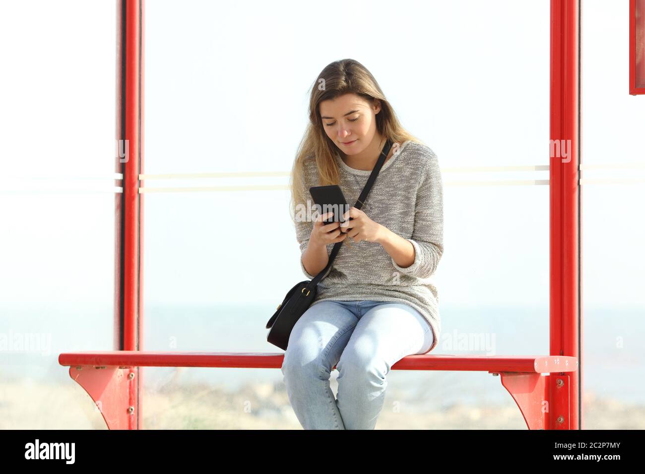 Girl checking mobile phone information sitting and waiting in a bus ...
