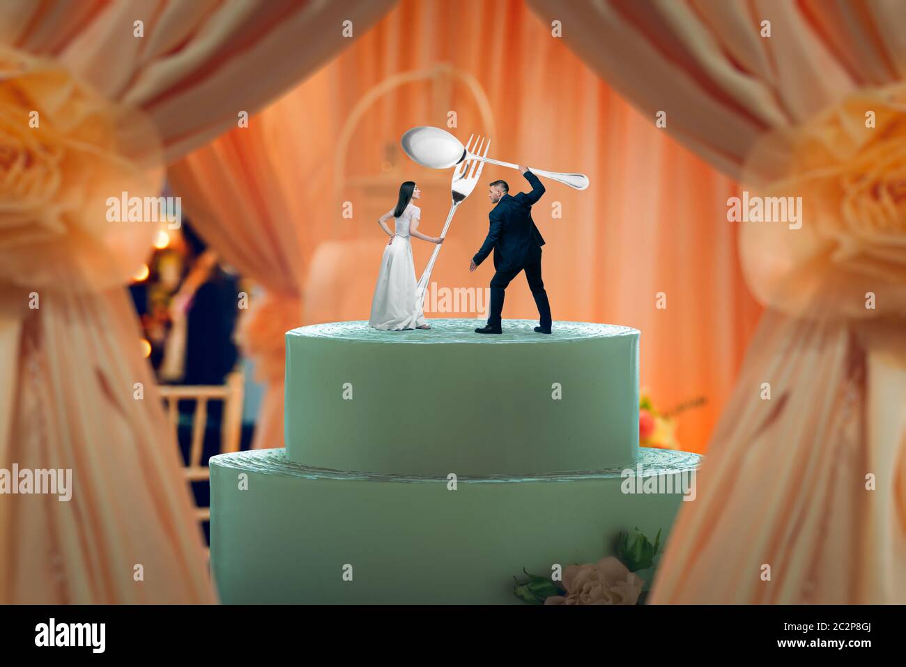 Wedding cake, bride and groom figurines hold huge cutlery in their ...