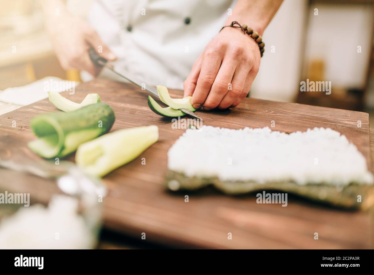 Male cook hands closeup, making sushi rolls on the kitchen. Traditional ...