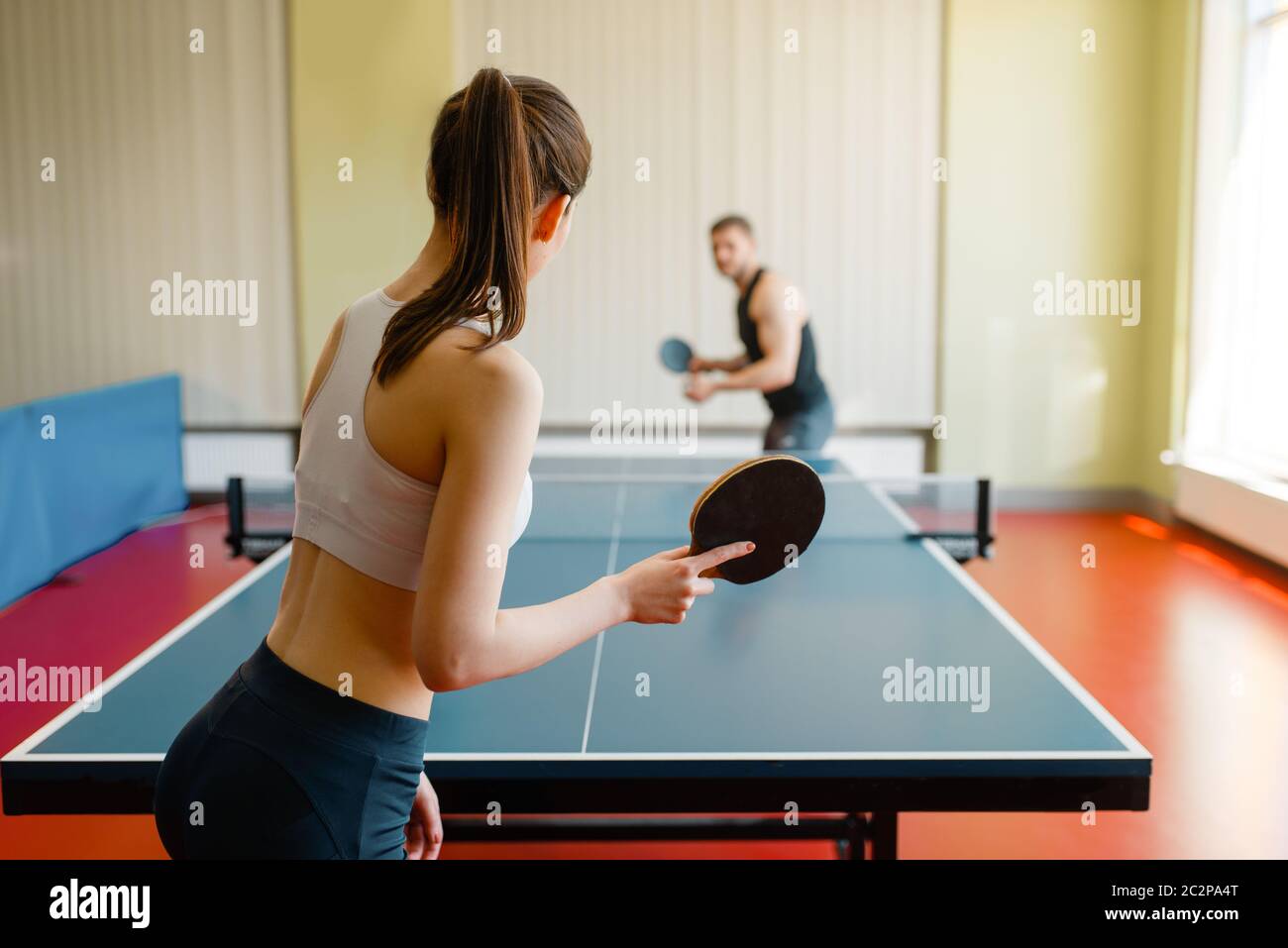 Man and woman playing ping pong indoors. Couple in sportswear holds ...
