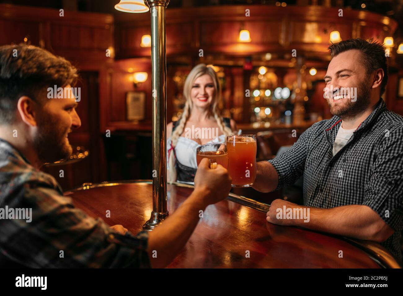 Friends clinking mugs in beer bar, waitress at the counter on ...