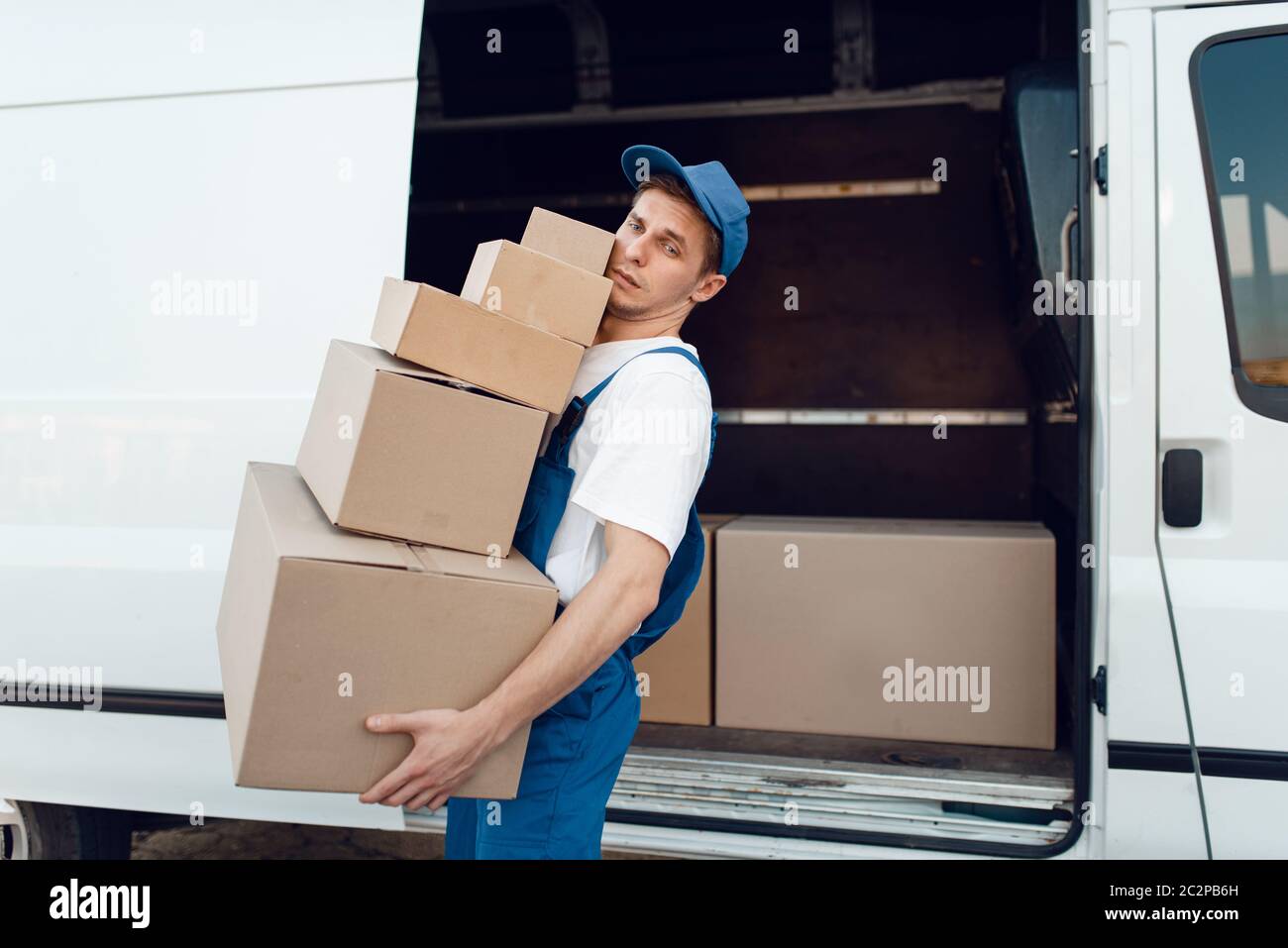 Mailman in uniform unloads the car with parcels, delivery service. Man ...