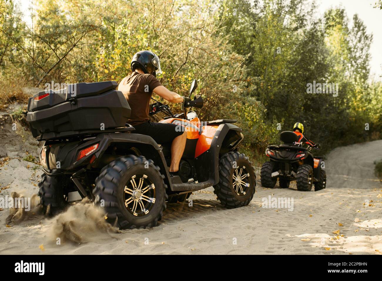 Two quad bike riders in helmets travels in forest, front view. Riding ...