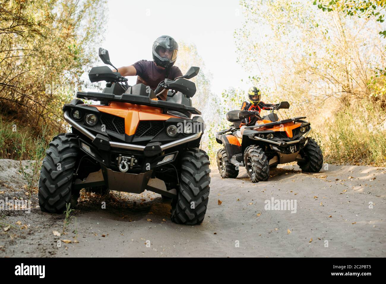 Two quad bike riders in helmets travels in forest, front view. Riding ...