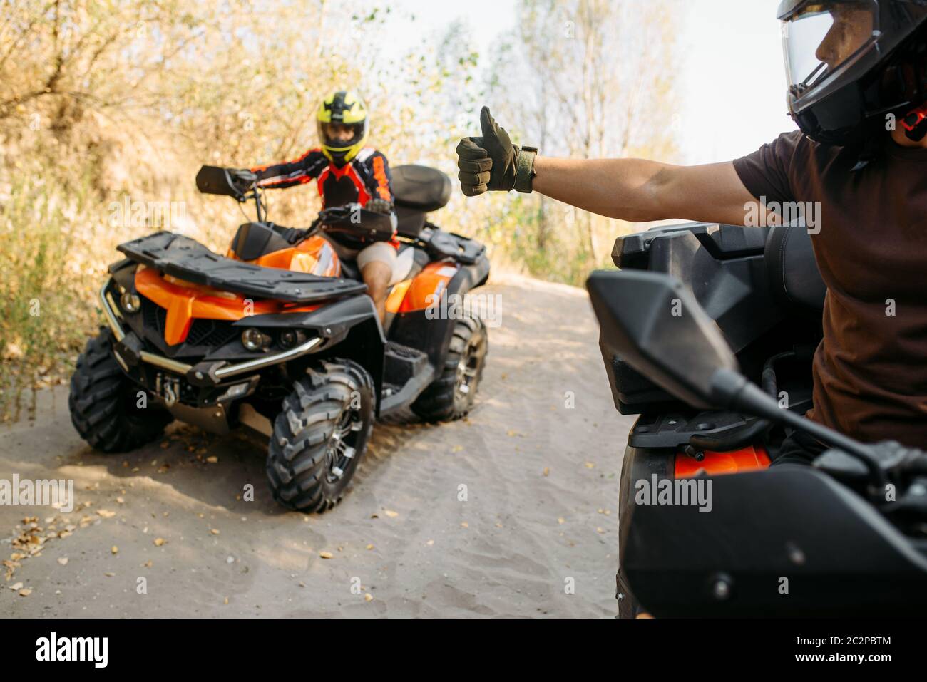 ATV rider in helmet showing thumbs up to his partner, offroad trip in ...
