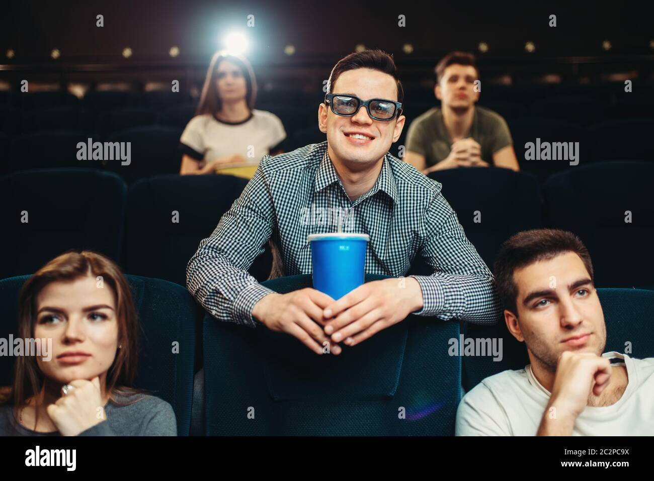 Young smiling man in 3d glasses holds beverage and poses in cinema ...