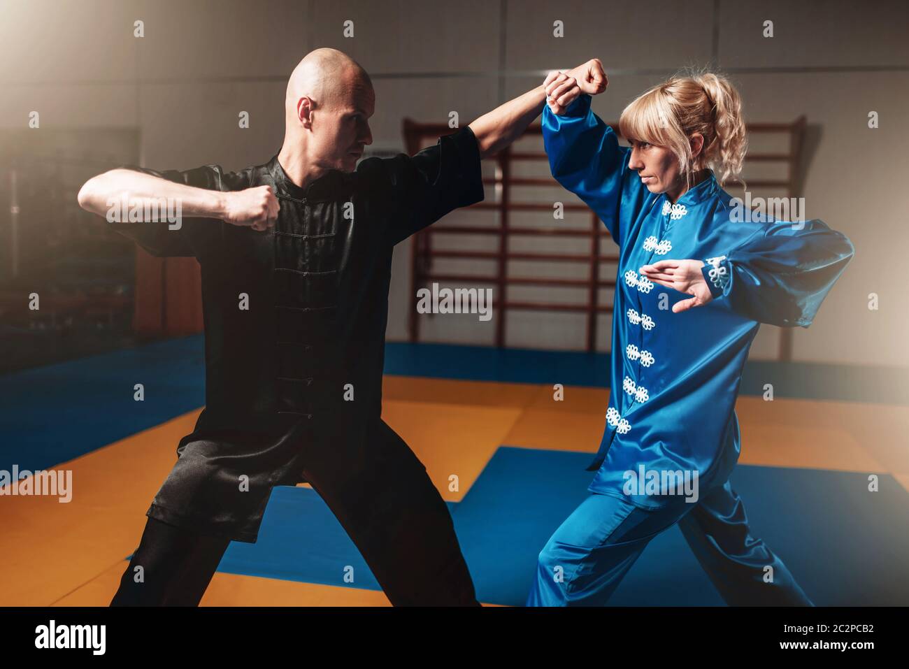 Male and female wushu fighters exercises indoor, martial arts. Sparring ...