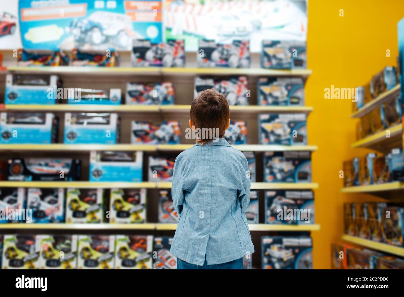 Little boy at the shelf in kids store, back view. Son choosing toys in ...