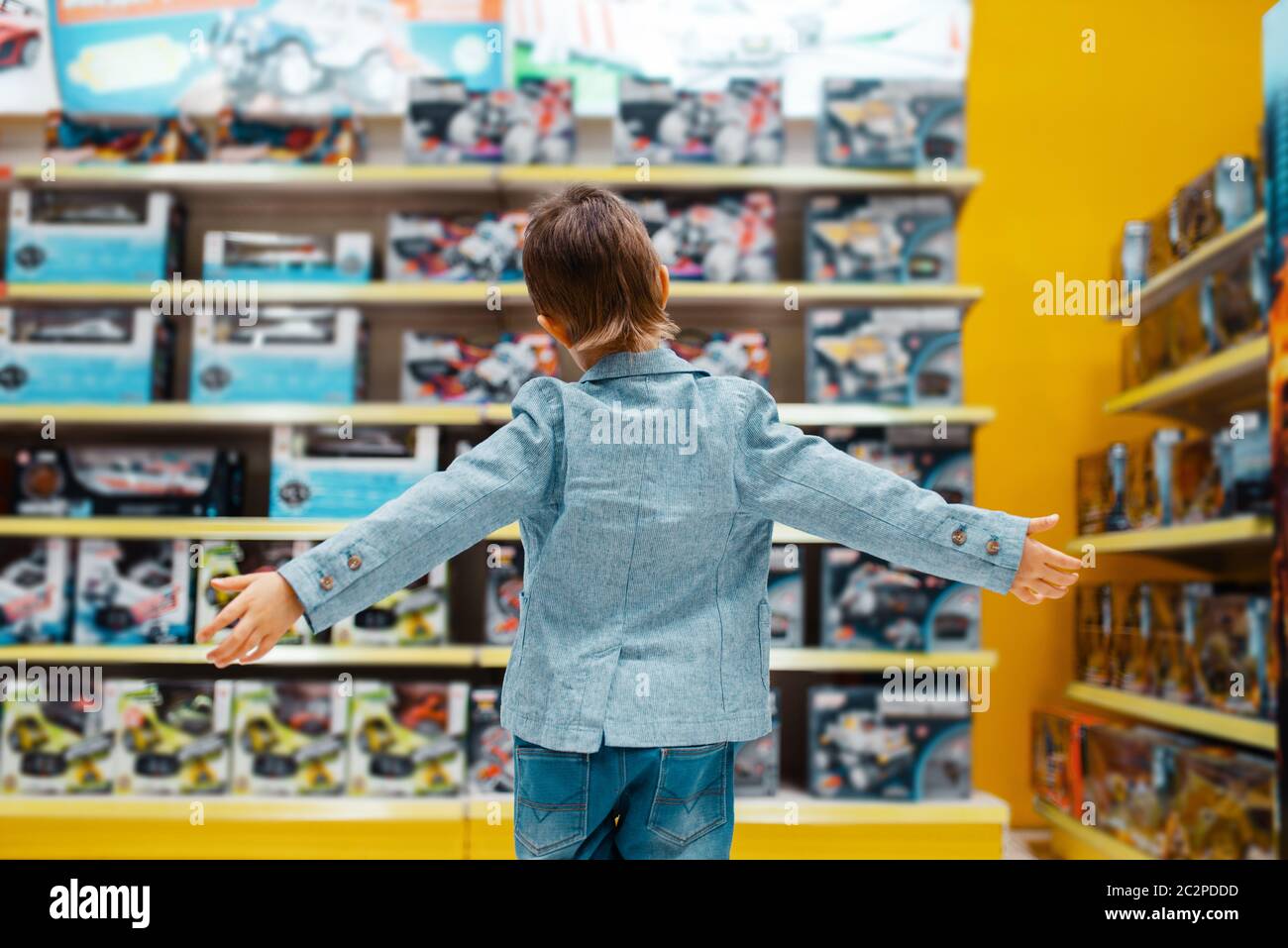Little boy at the shelf in kids store, back view. Son choosing toys in ...