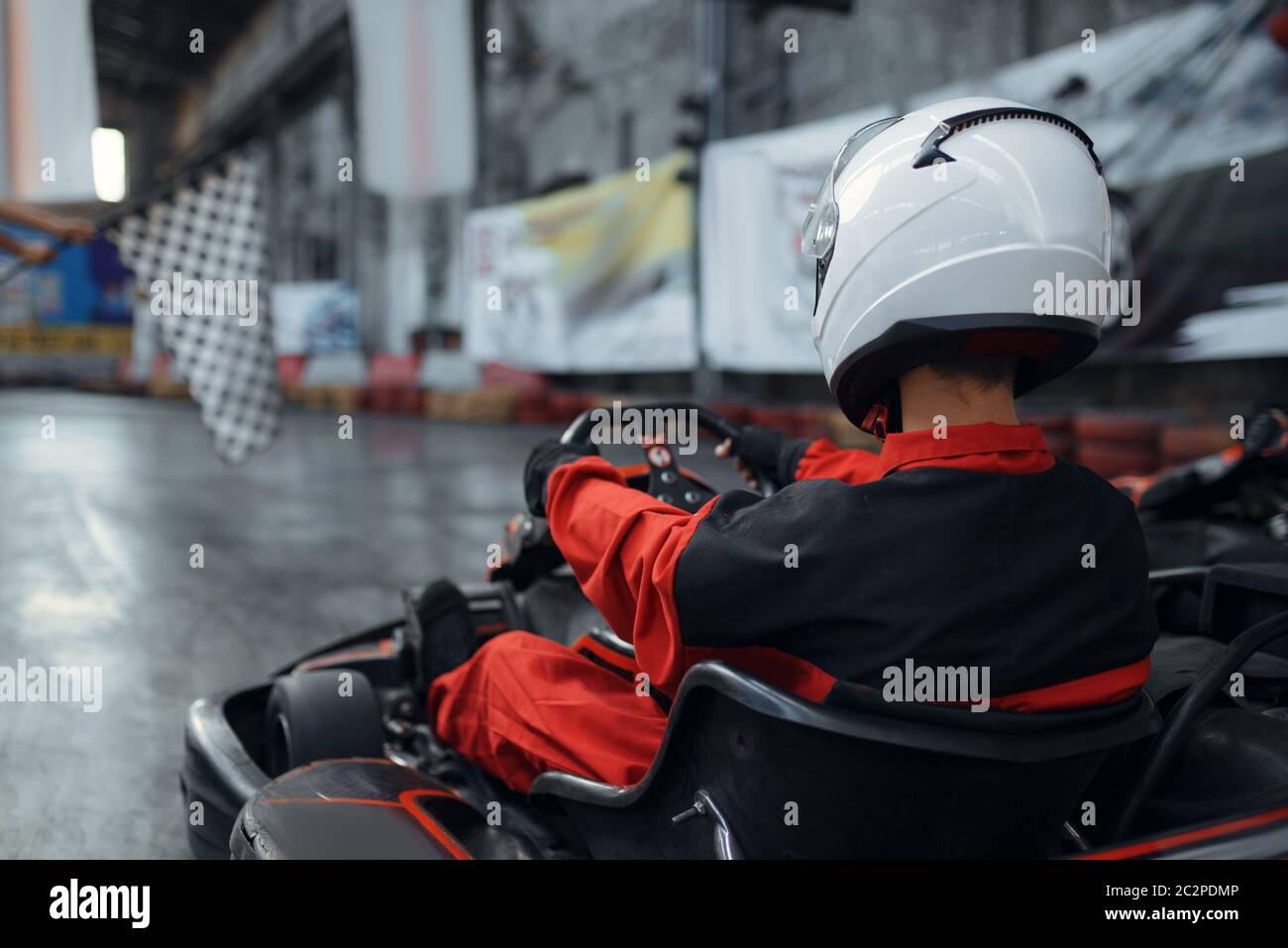 Kart racer in helmet, back view, karting auto sport indoor. Speed race ...