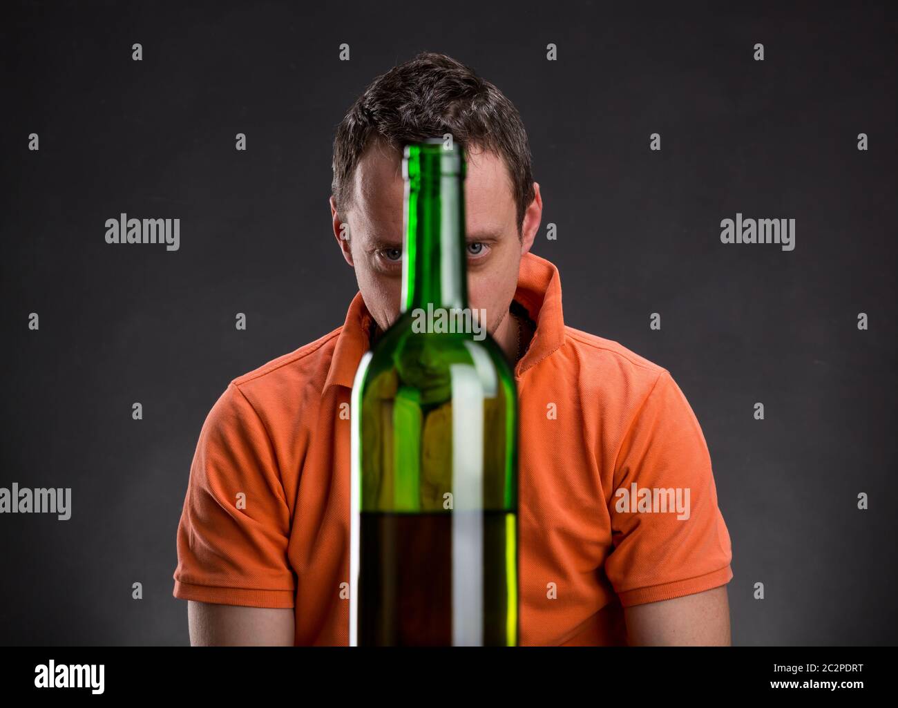Alcohol addict looks at the bottle Stock Photo - Alamy