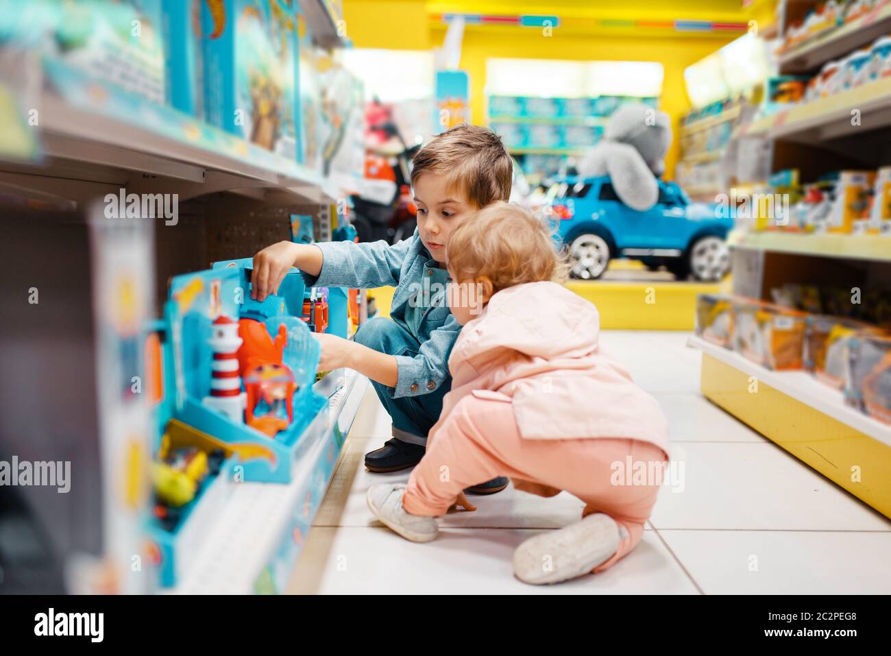 Little boy and girl at the shelf in kids store, side view. Brother and ...