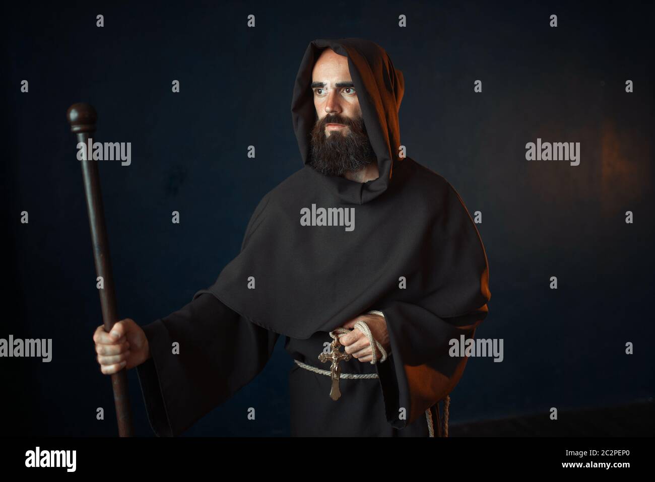 Medieval monk with wooden stick and cross in hands, religion ...