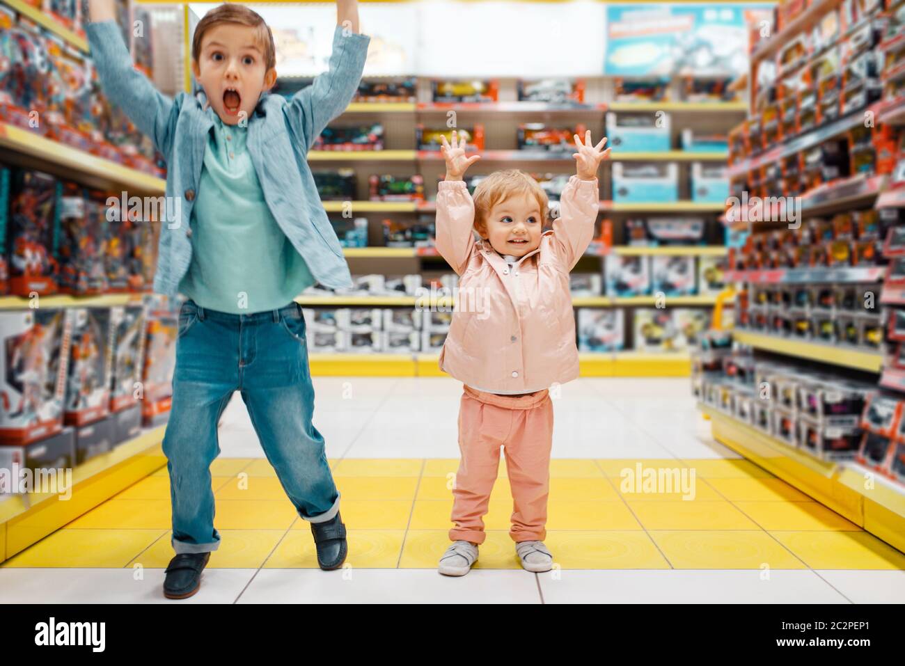 Little boy and girl raised their hands up at the shelf in kids store ...