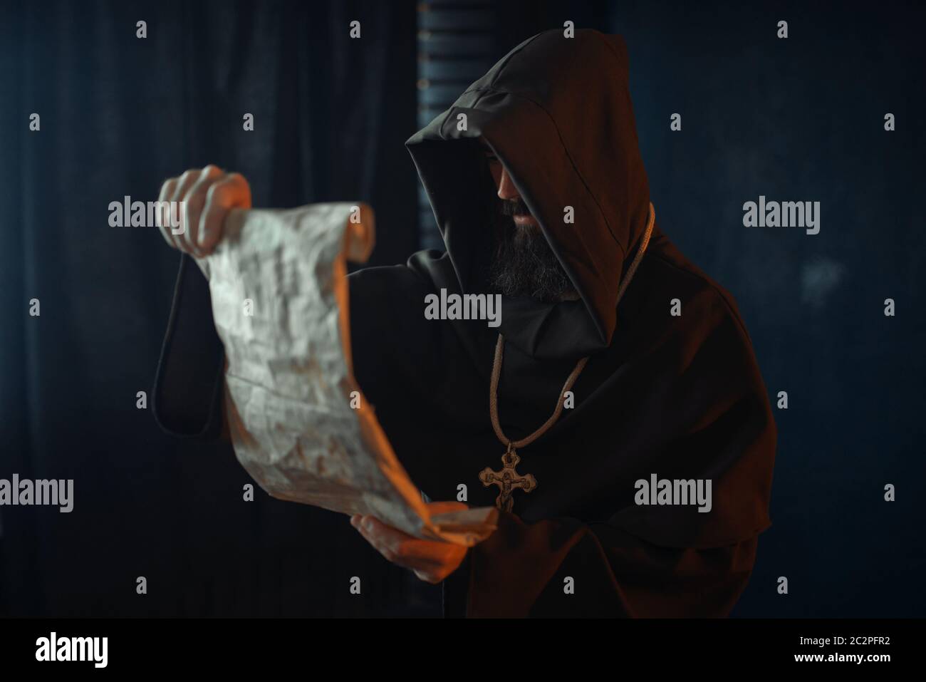 Medieval monk with an evil face reading a prayer in the ancient ...