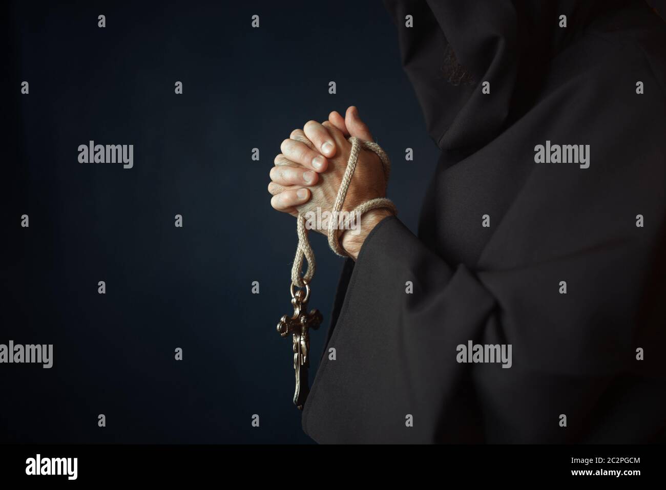Medieval friar praying with wooden cross in hands in church, secret ...