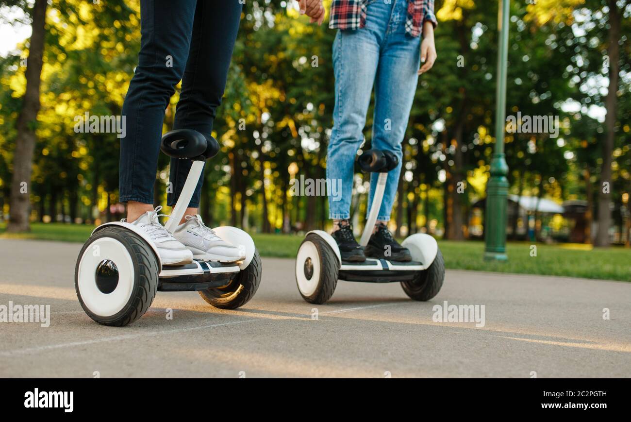 Male and female person riding on gyro board in park. Outdoor recreation ...