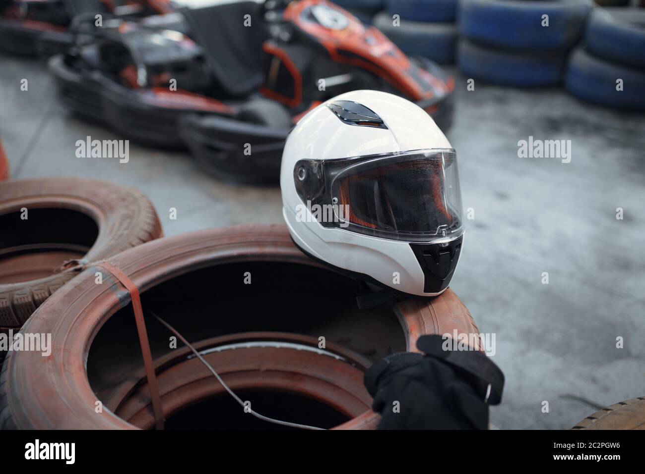 Helmet on tires, go kart car on background, karting auto sport indoor ...