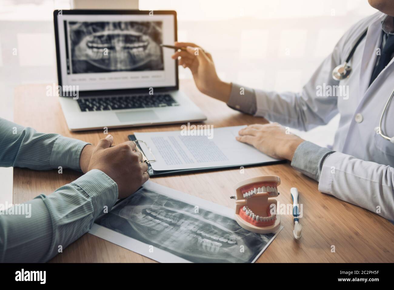 Dentist hand pointing x-ray picture in laptop computer and talking to ...