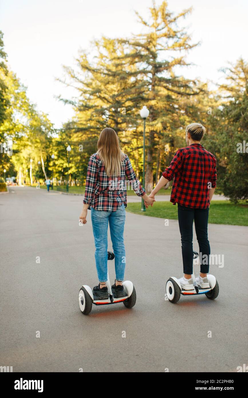 Young couple riding on gyro board in park, back view. Outdoor ...