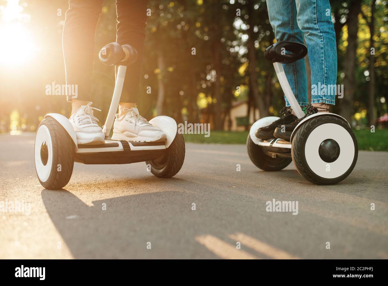 Male and female person riding on gyro board in park at sunset. Outdoor ...