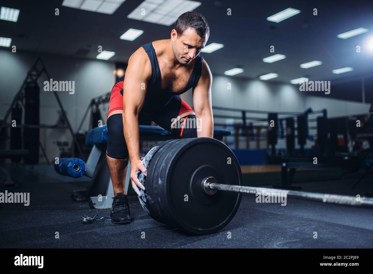 Male powerlifter prepares a barbell for deadlift in gym. Weightlifting ...