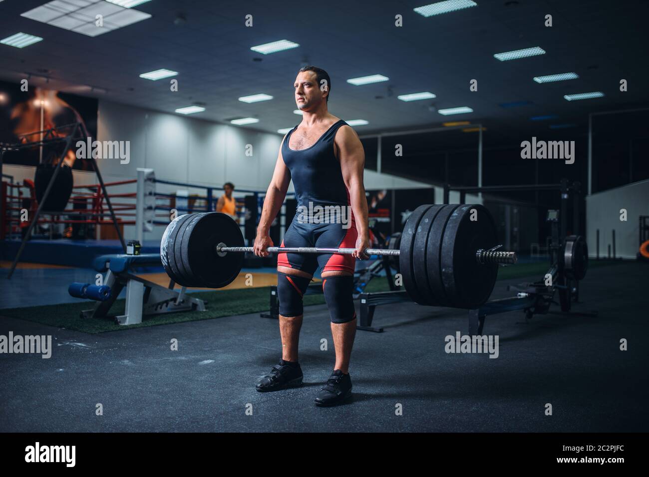 Strong male powerlifter keeps the weight of heavy barbell in gym ...