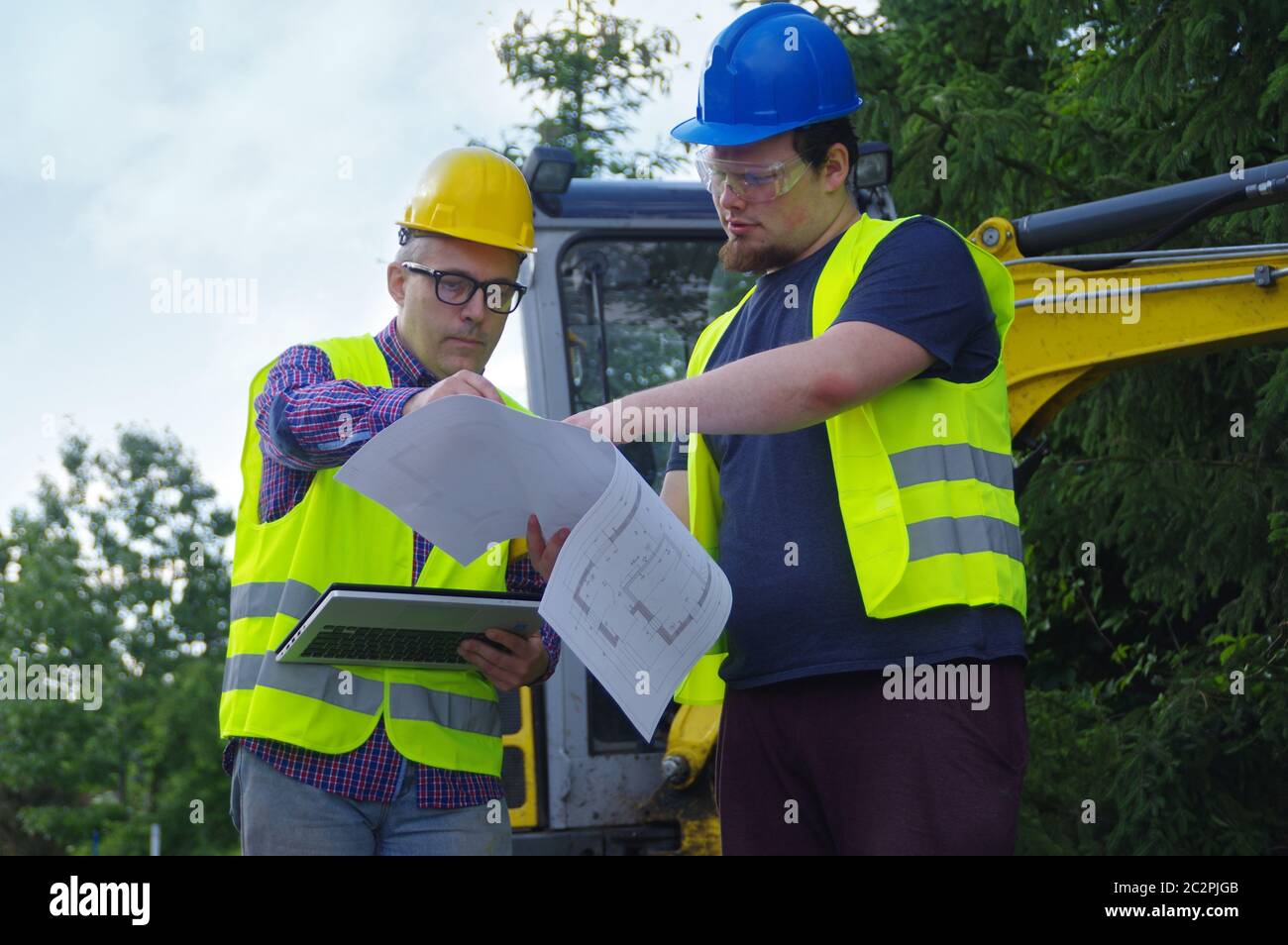 Engineer and worker on construction site with excavator in the ...